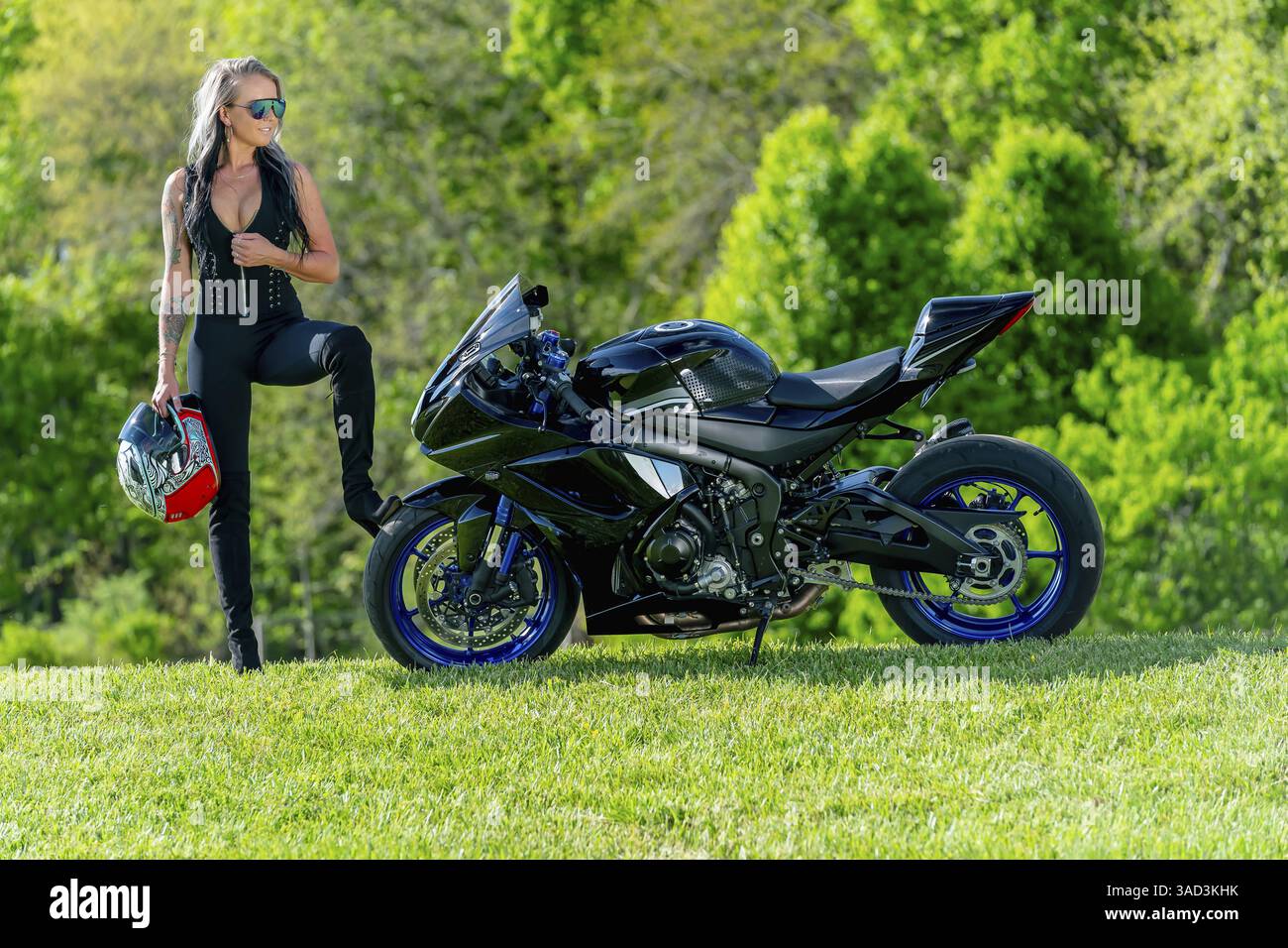 A stunning woman strikes a confident pose beside her high-performance ...