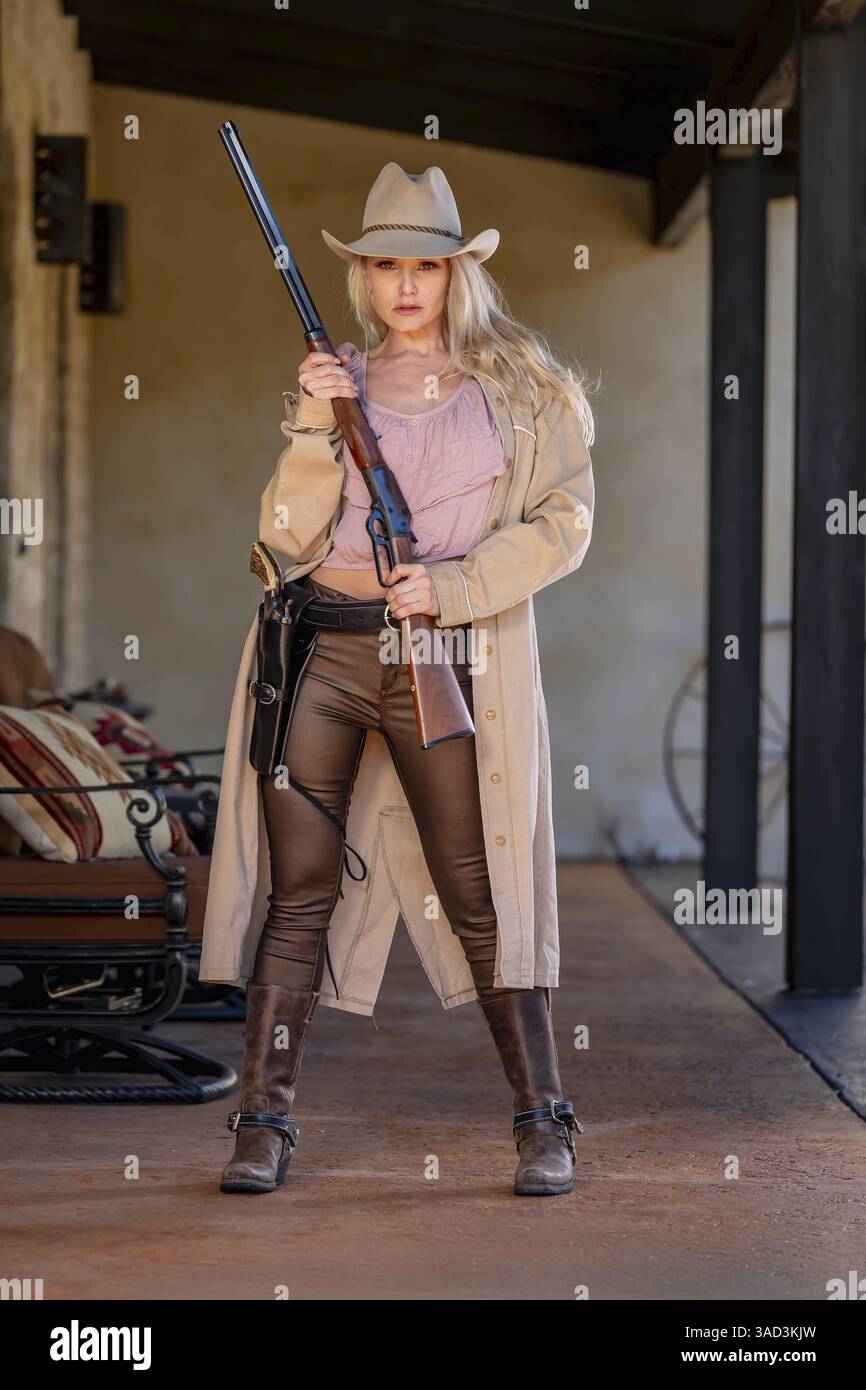 A confident, beautiful blonde woman in classic cowboy attire stands ...