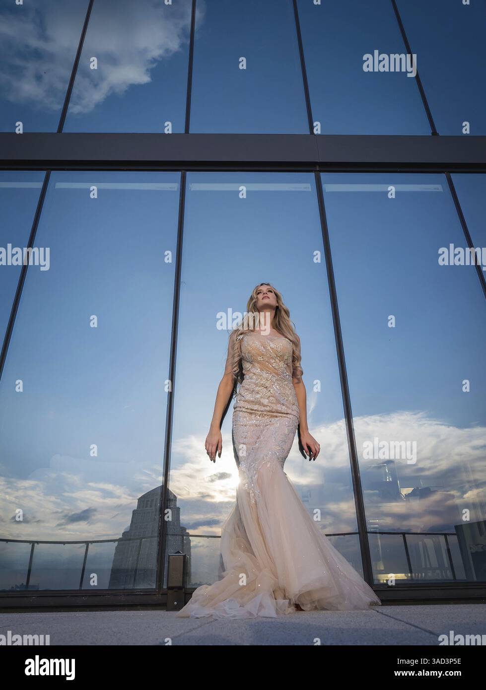 A beautiful blonde model, glowing in the sunlight, poses outdoors in a ...