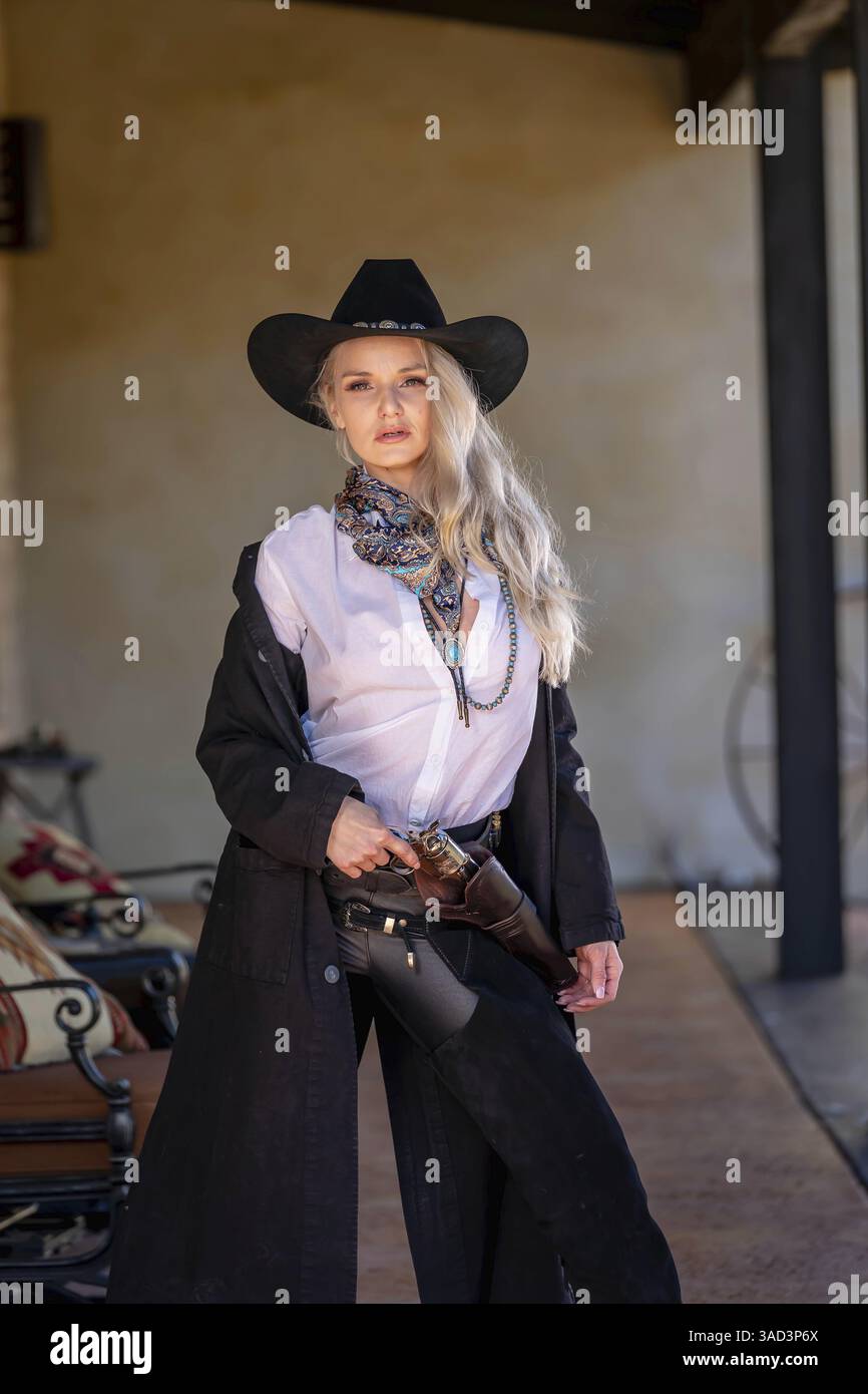A confident, beautiful blonde woman in classic cowboy attire stands ...