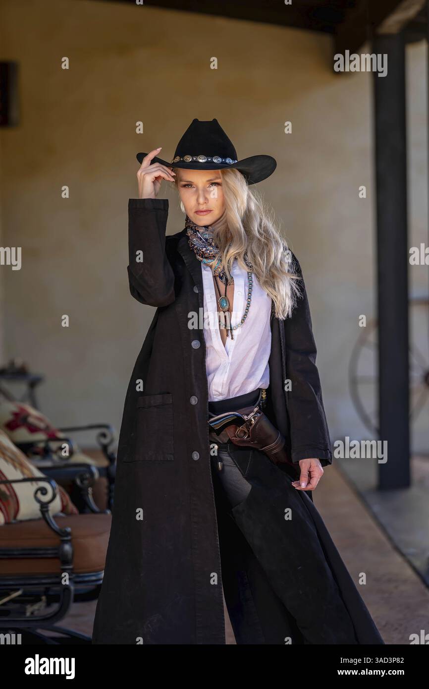 A confident, beautiful blonde woman in classic cowboy attire stands ...