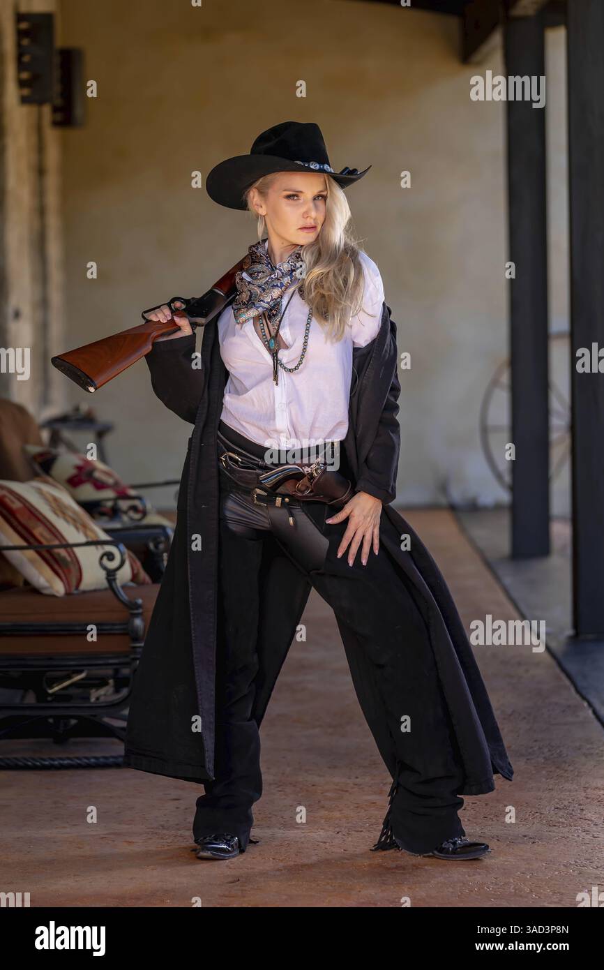 A confident, beautiful blonde woman in classic cowboy attire stands ...