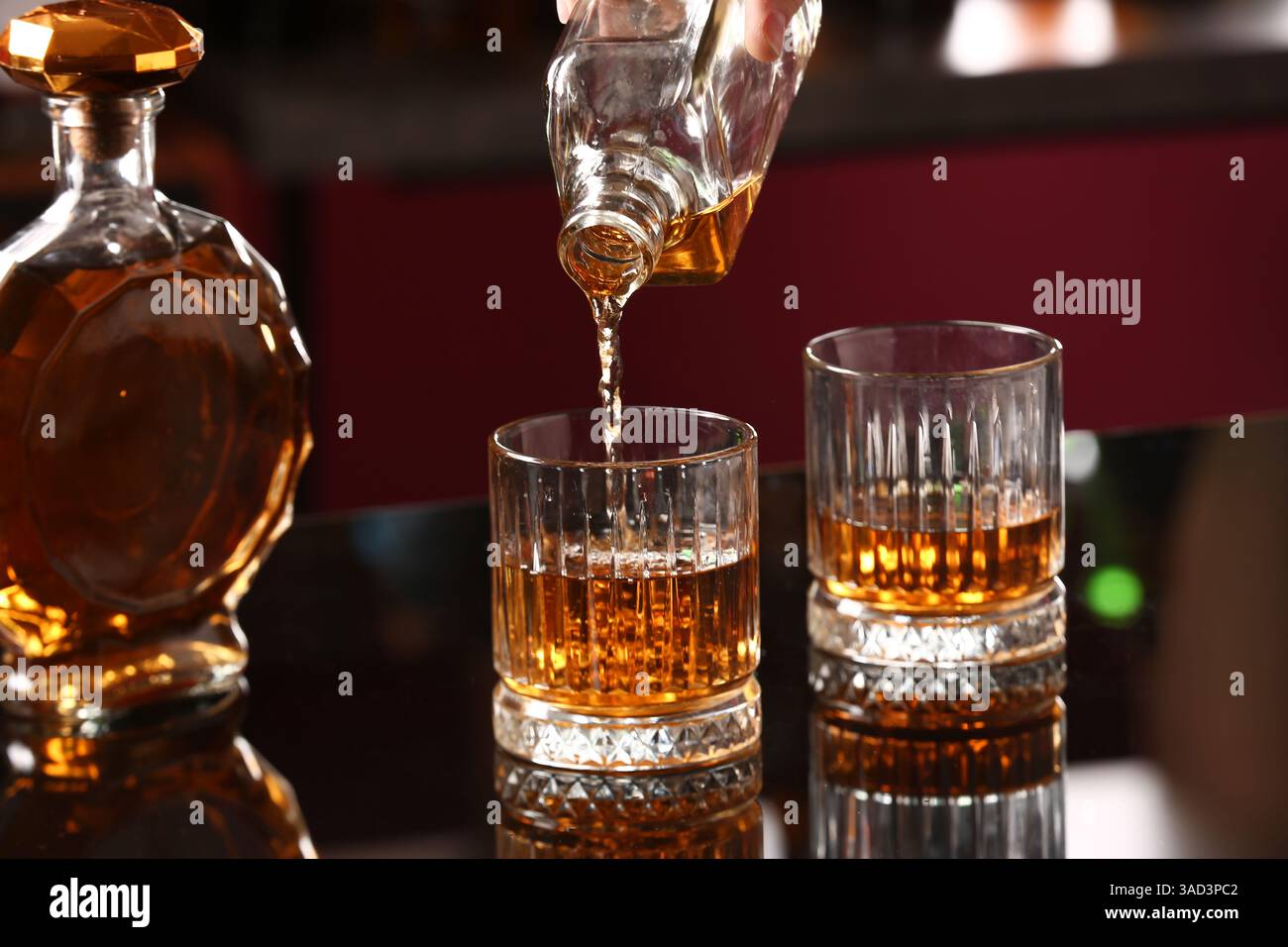 Pouring of cold rum from bottle into glasses at table in bar Stock ...