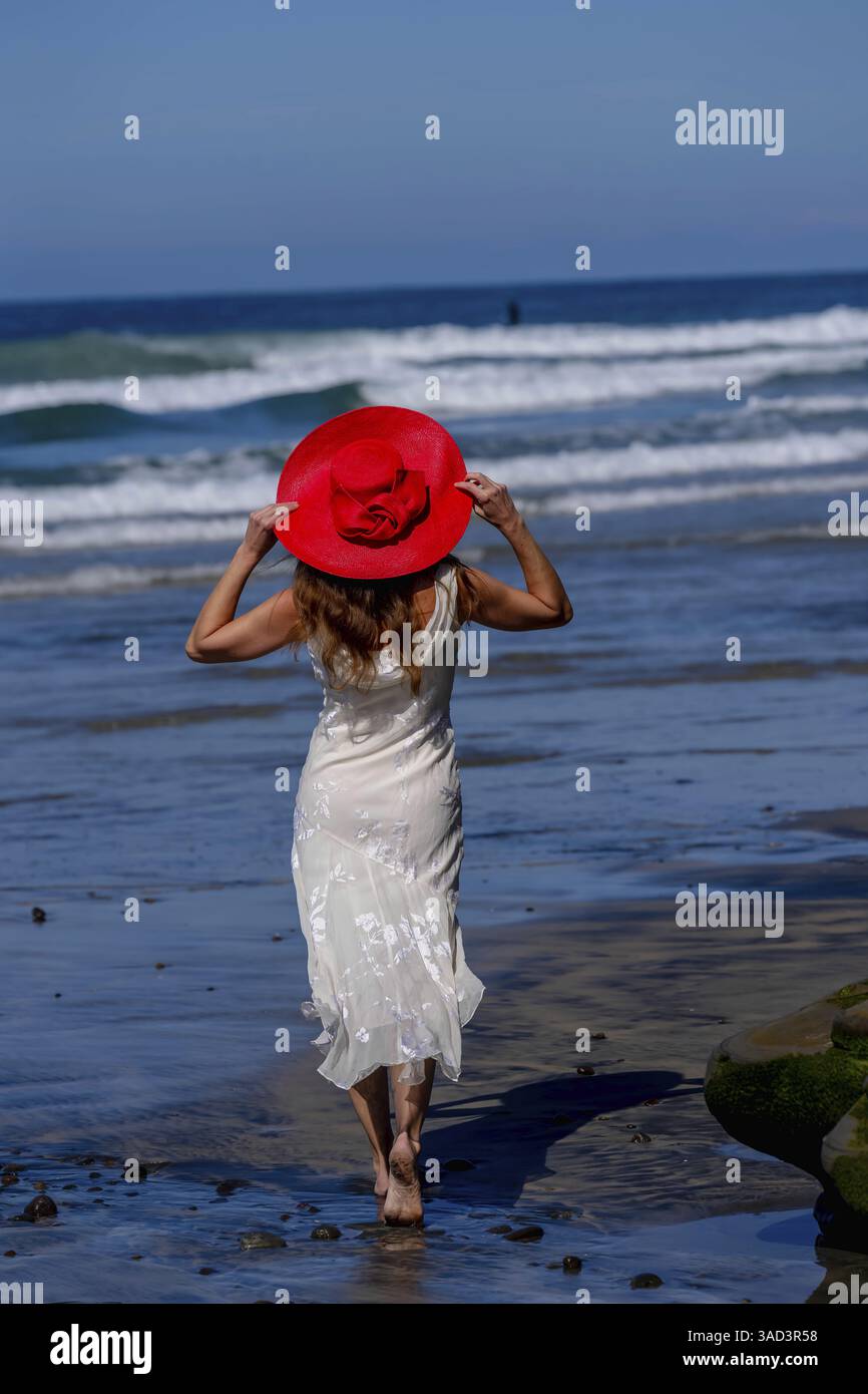 Breathtaking woman basks in beach bliss, near a pier, under clear blue ...
