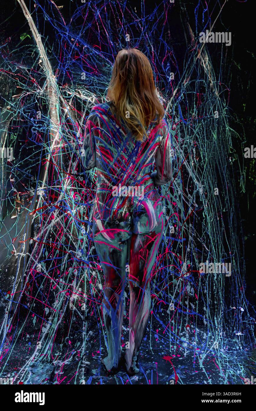 A model poses gracefully, her body adorned in vibrant body paint, with brilliant, sweeping ...