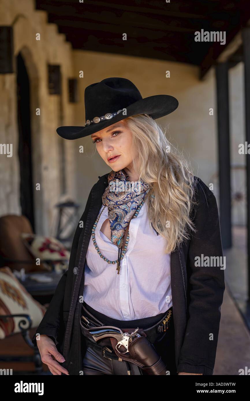A confident, beautiful blonde woman in classic cowboy attire stands ...