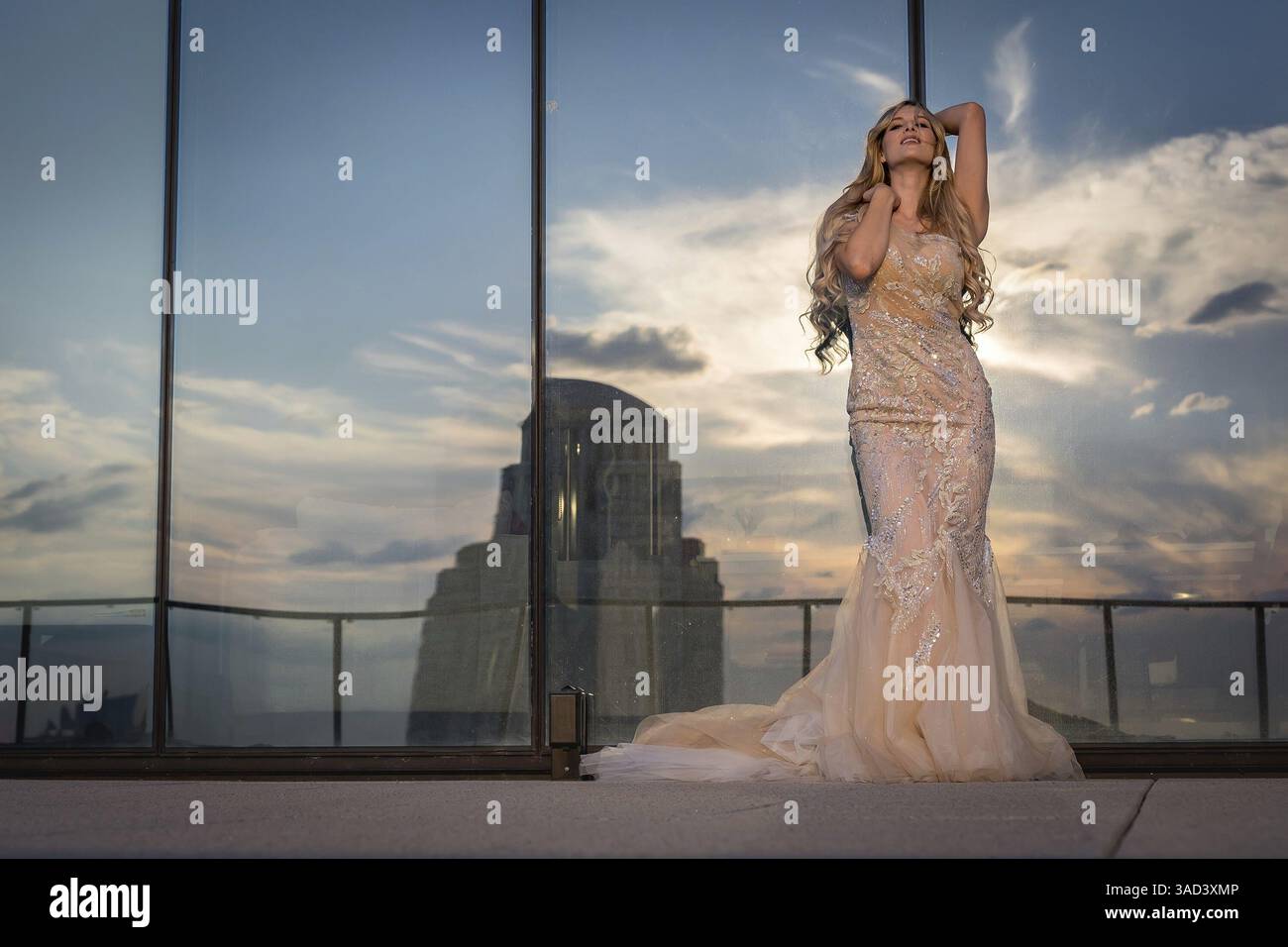 A beautiful blonde model, glowing in the sunlight, poses outdoors in a ...