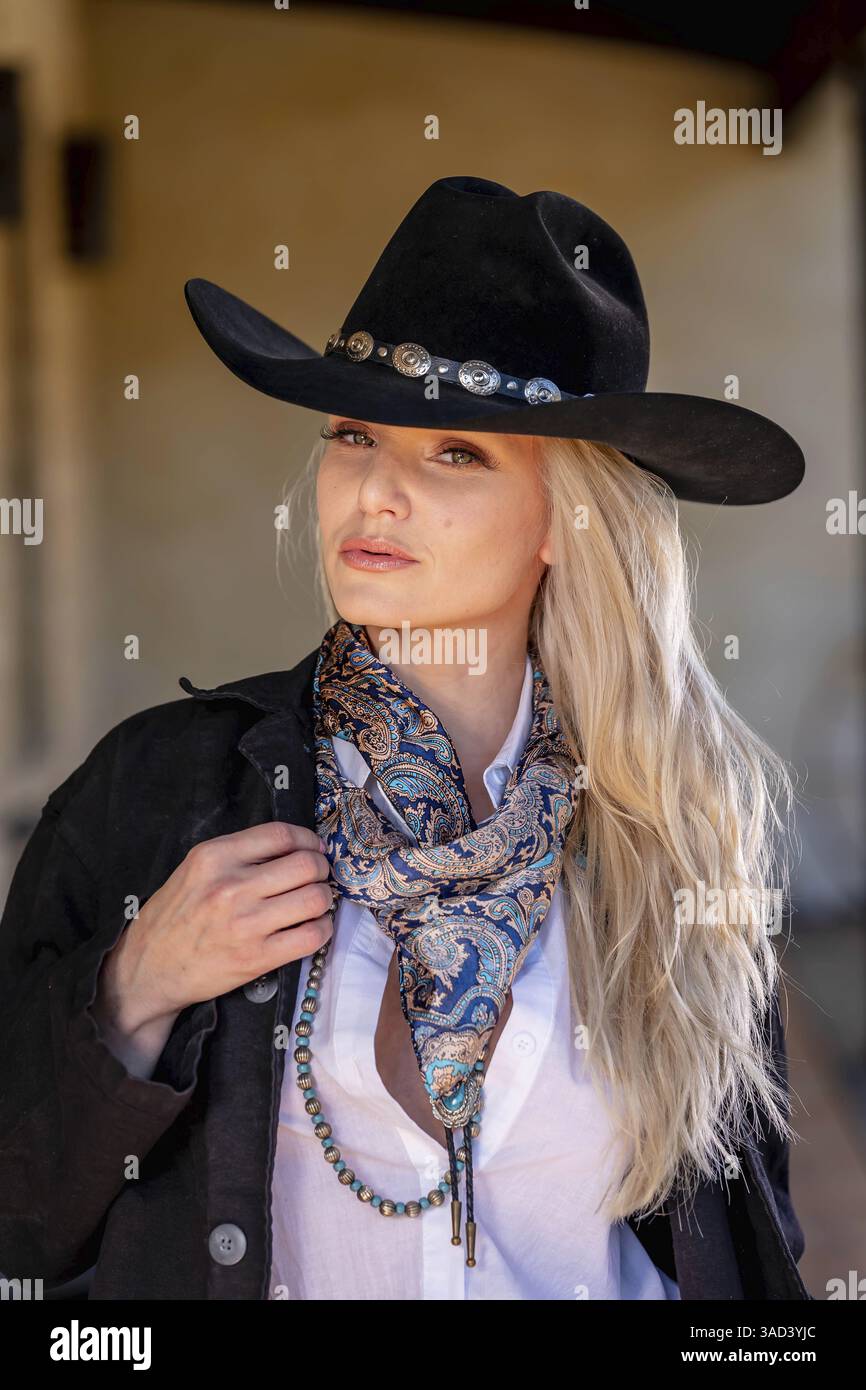 A confident, beautiful blonde woman in classic cowboy attire stands ...