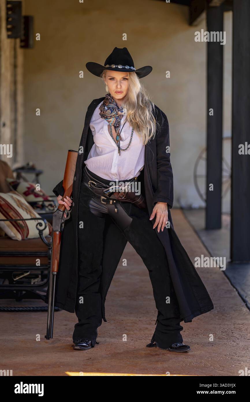A confident, beautiful blonde woman in classic cowboy attire stands ...