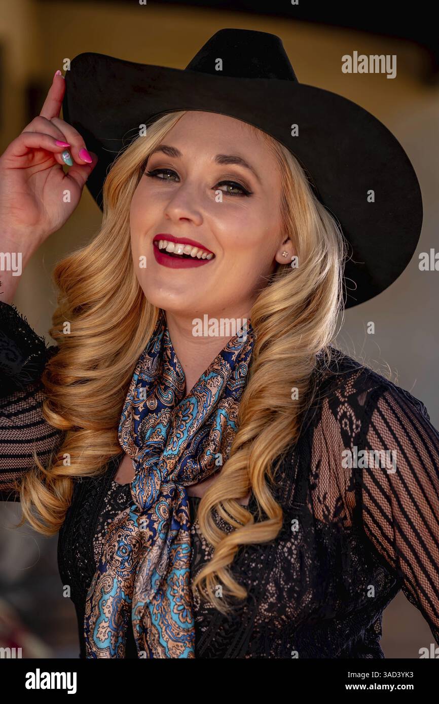 A confident, beautiful blonde woman in classic cowboy attire stands ...