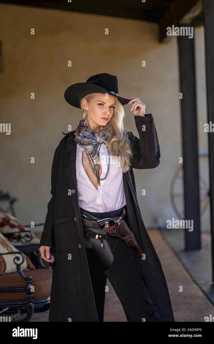 A confident, beautiful blonde woman in classic cowboy attire stands ...