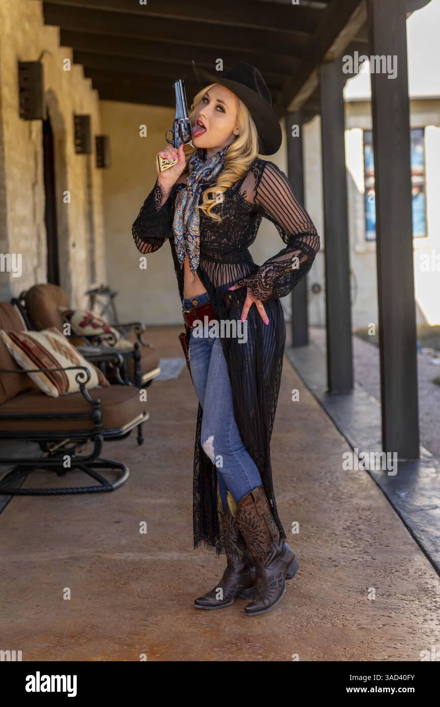 A confident, beautiful blonde woman in classic cowboy attire stands ...