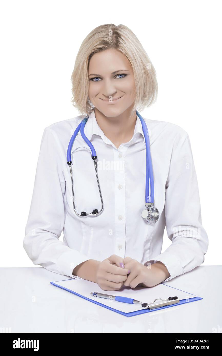 Beautiful young female doctor sitting near the table looking at camera ...