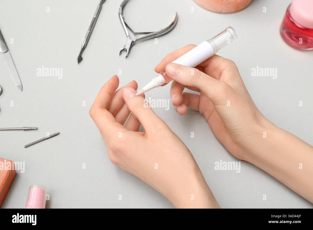 Female hands applying cuticle oil with pen, cosmetics and manicure ...