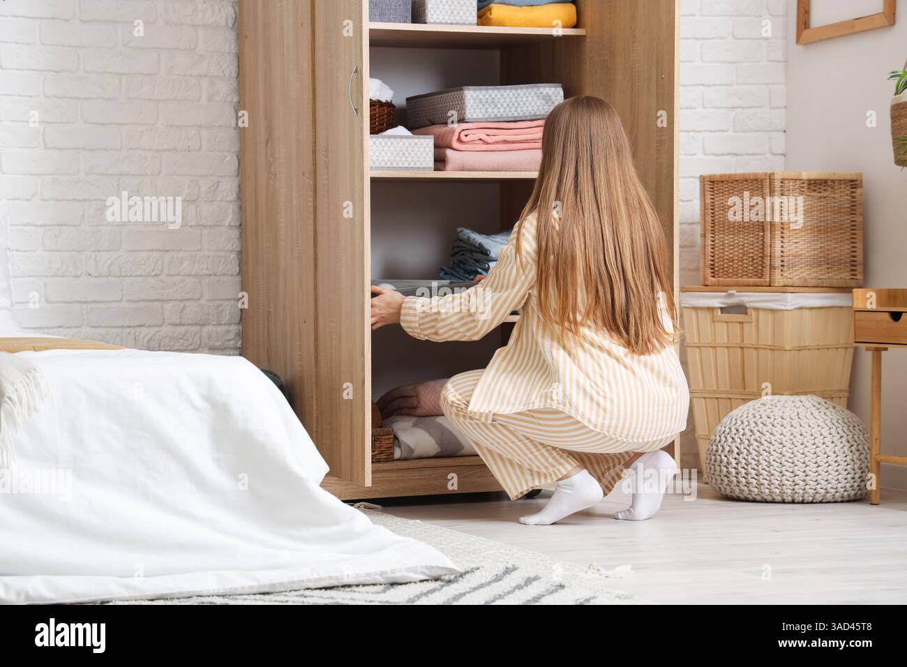 Young woman folding clean clothes in wardrobe Stock Photo - Alamy