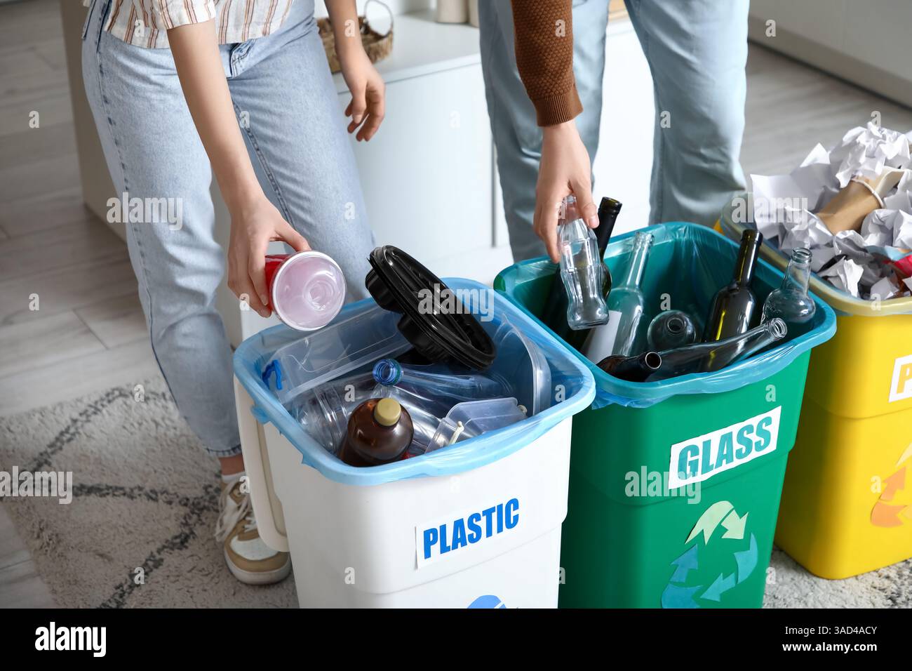 Young couple sorting rubbish in garbage bins at home, closeup. Global ...