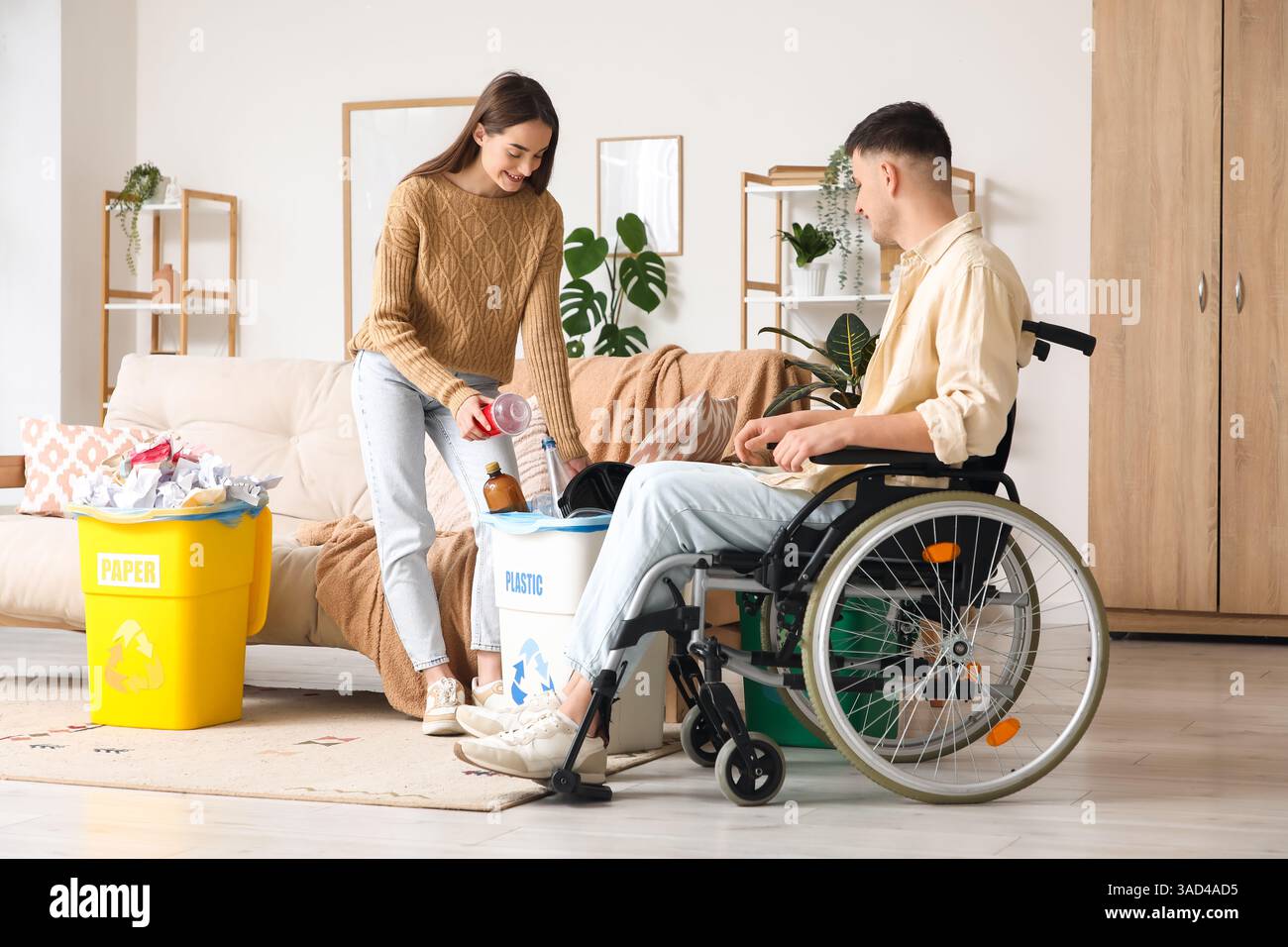 Young man in wheelchair and his girlfriend sorting rubbish in garbage ...