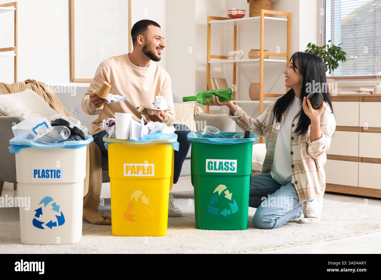 Young couple sorting rubbish in garbage bins at home. Global Recycling ...