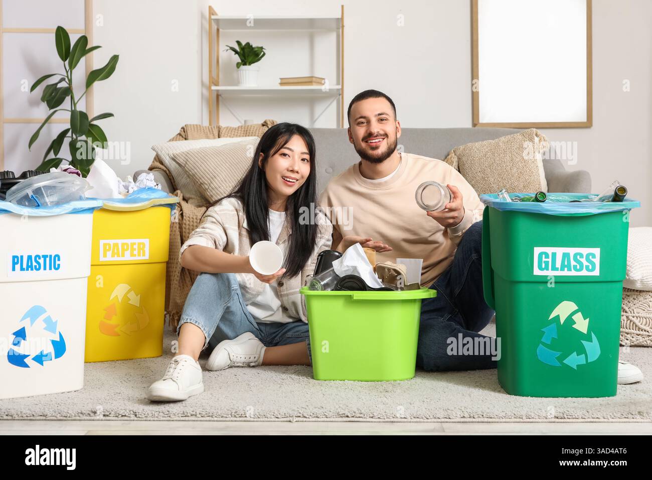 Young couple sorting rubbish in garbage bins at home. Global Recycling ...