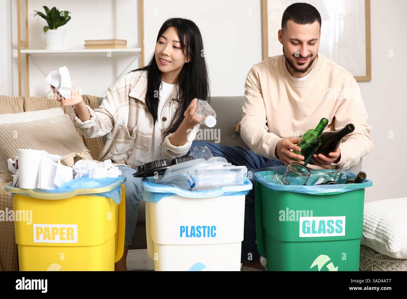 Young couple sorting rubbish in garbage bins at home. Global Recycling ...
