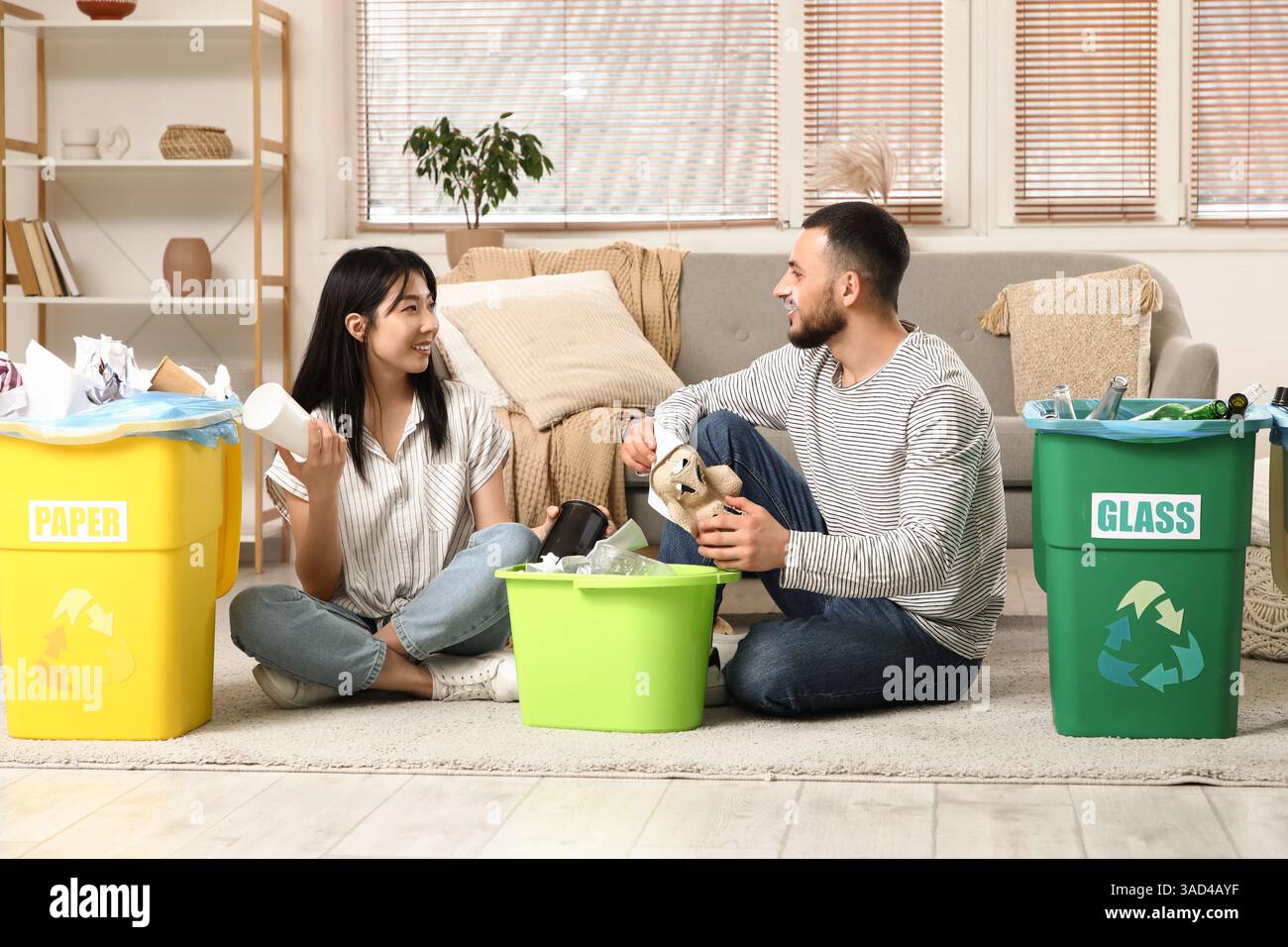 Young couple sorting rubbish in garbage bins at home. Global Recycling ...