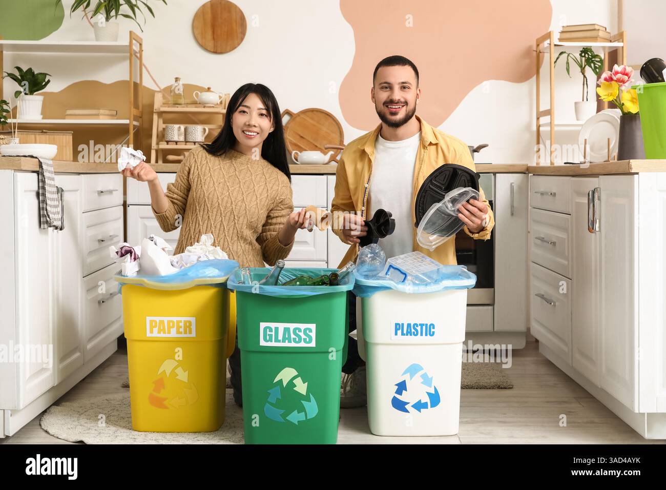 Young couple sorting rubbish in garbage bins at home. Global Recycling ...