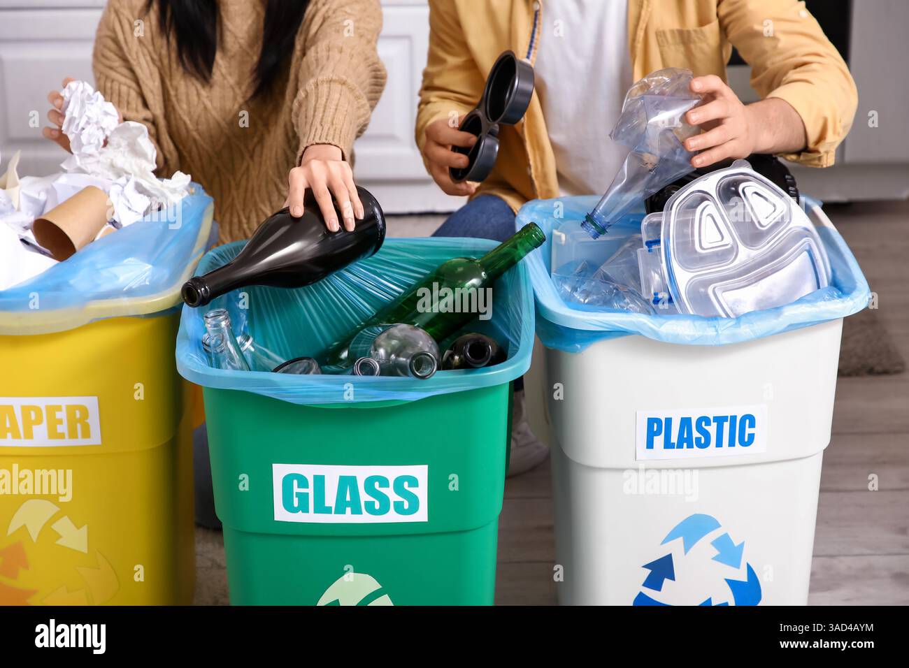 Young couple sorting rubbish in garbage bins at home, closeup. Global ...