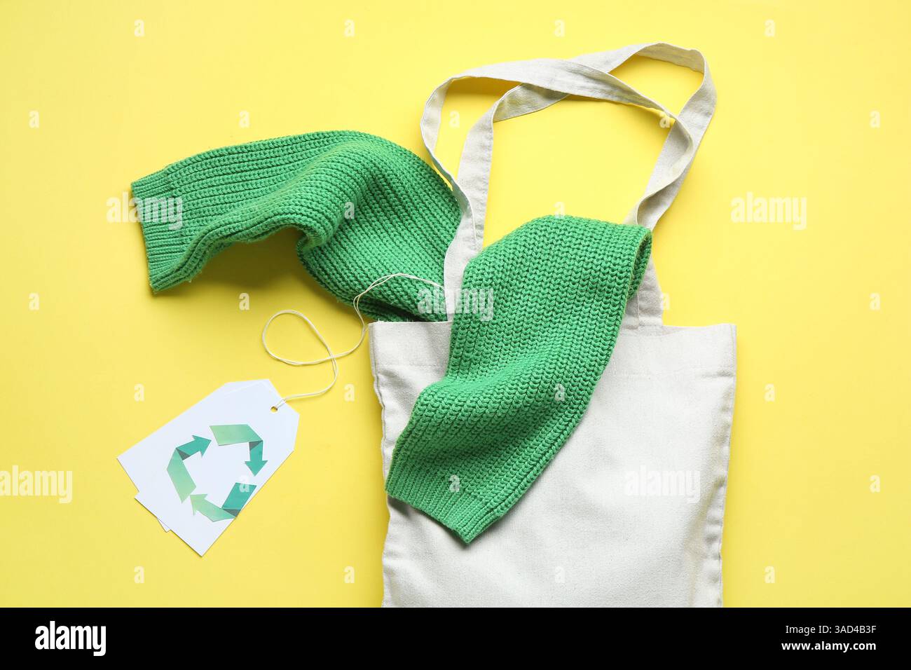 Bag with clothes and recycling tag on yellow background Stock Photo - Alamy