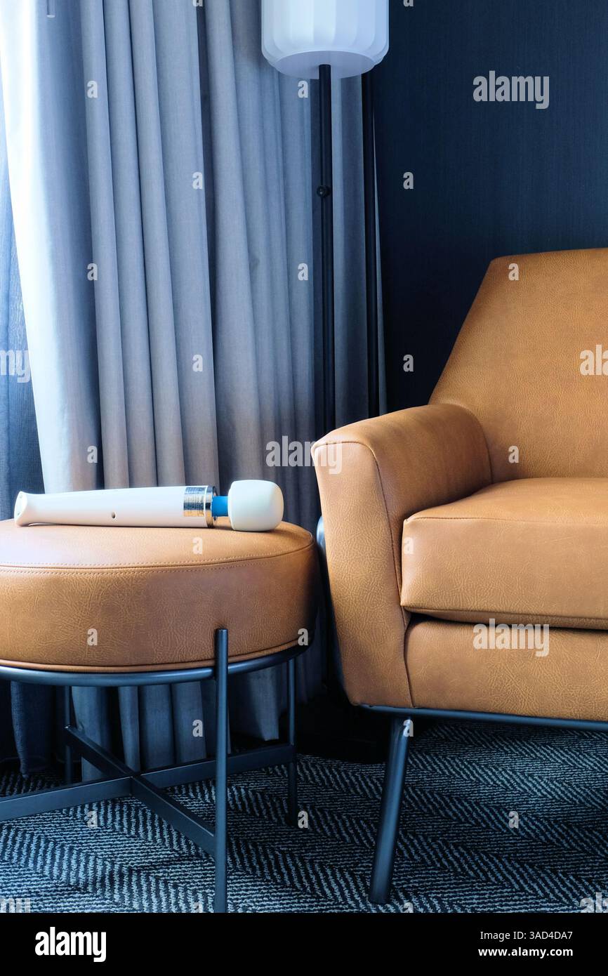 Cordless wand vibrator resting on a cushioned table next to a chair in ...