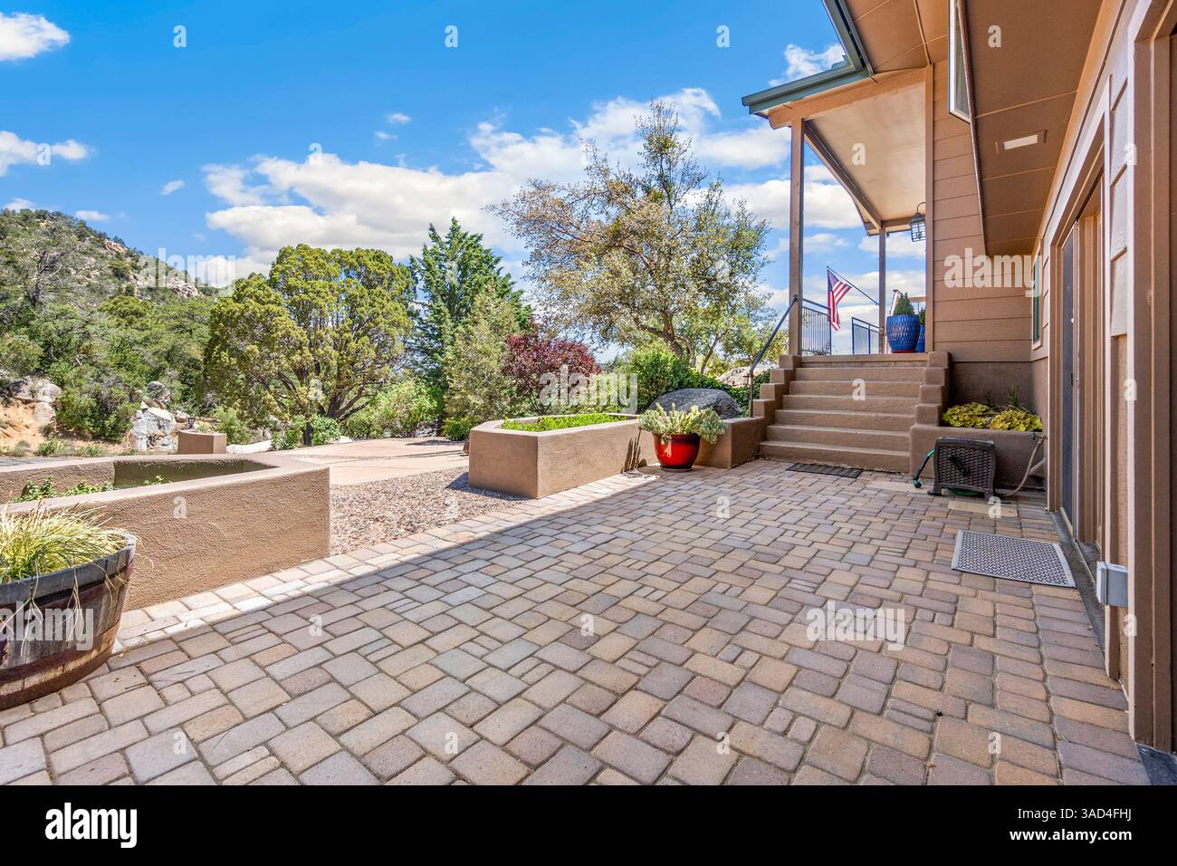 A large brick patio in front of a house with porch and stairs Stock ...