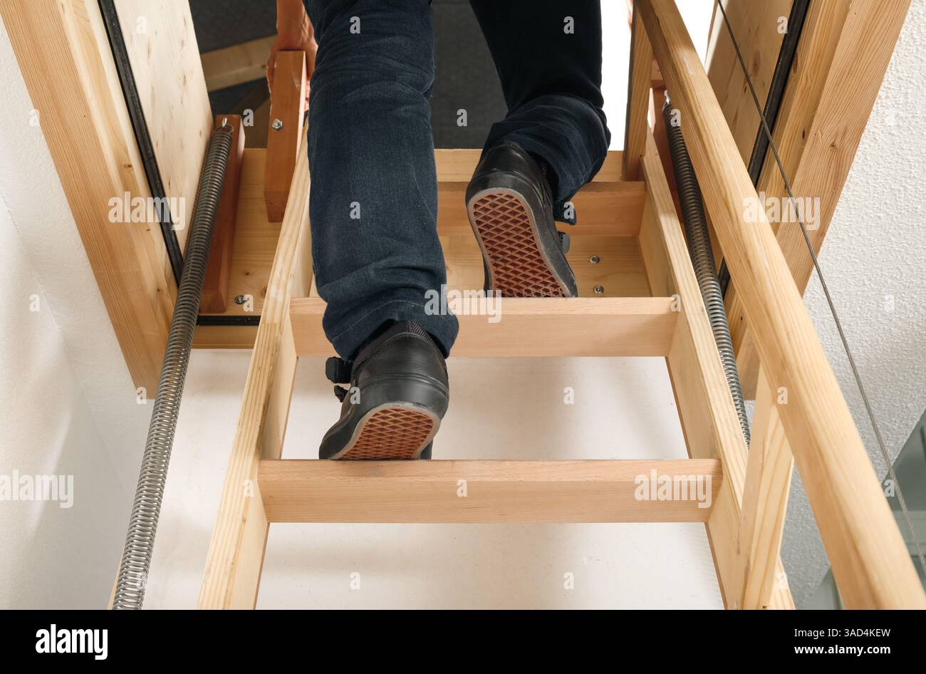 Back view of person using loft ladder or attic ladder. Woman climbing ...