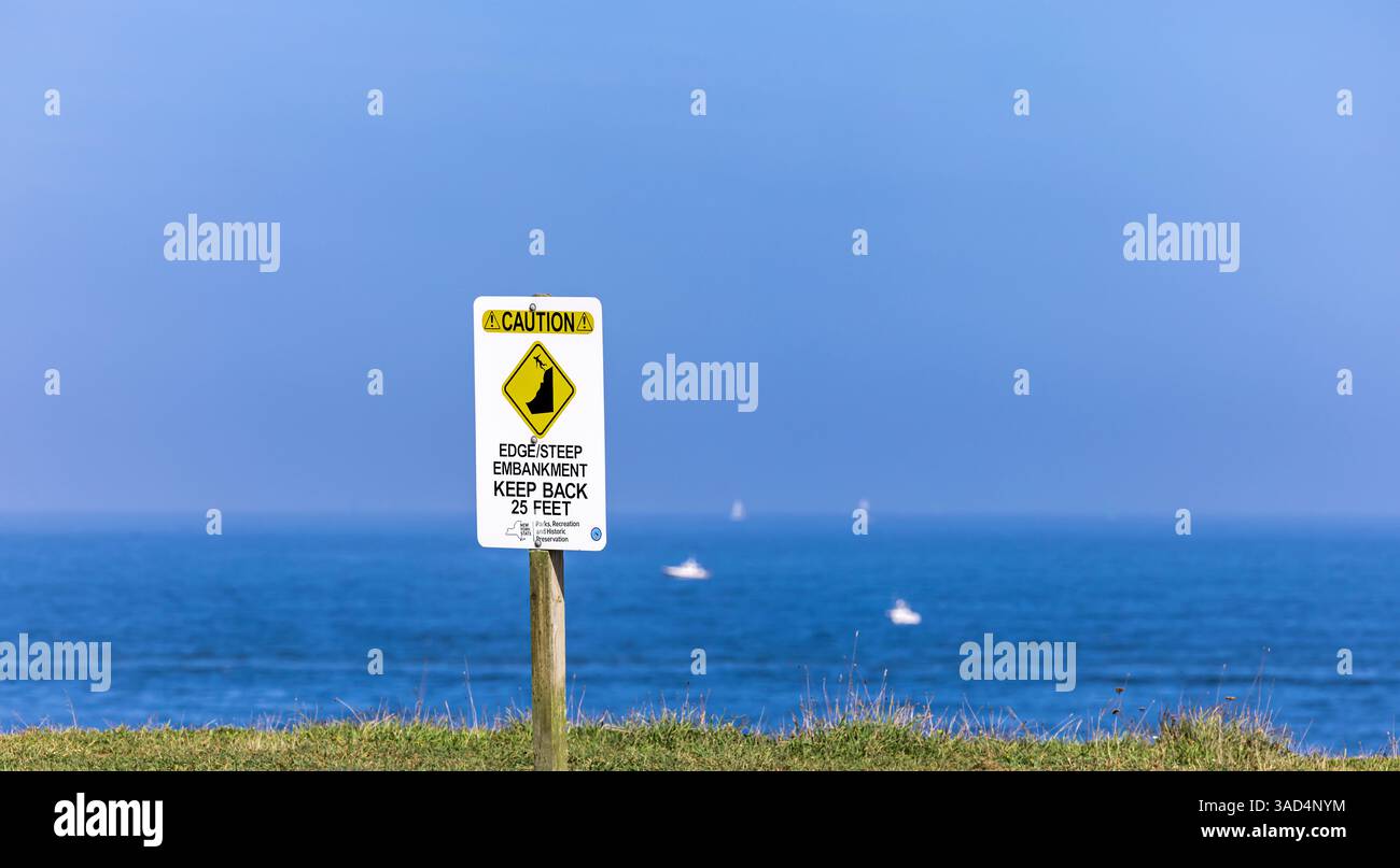 sign posted on the edge of a bluff in camp hero indicating caution ...