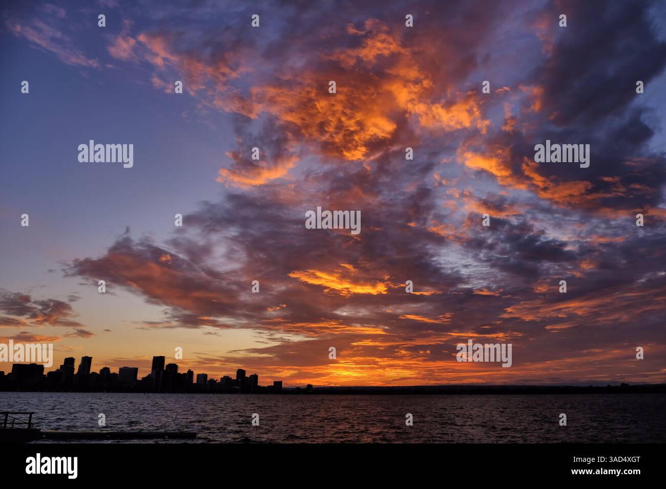 Perth city skyline and the Swan River silhouetted against a vivid ...