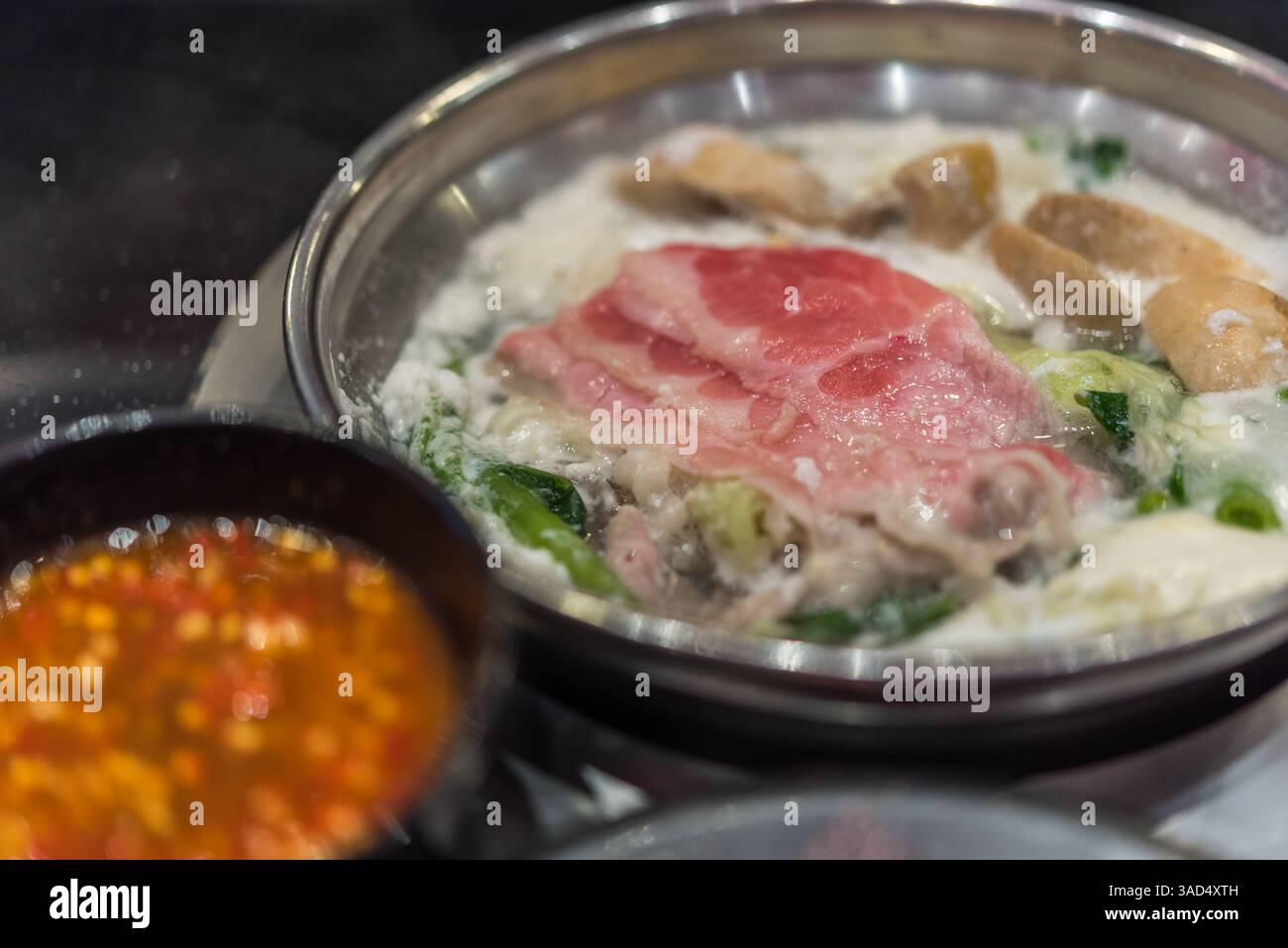 Cooking food by put a flesh beef, pork, egg and vegetable in to a hot ...