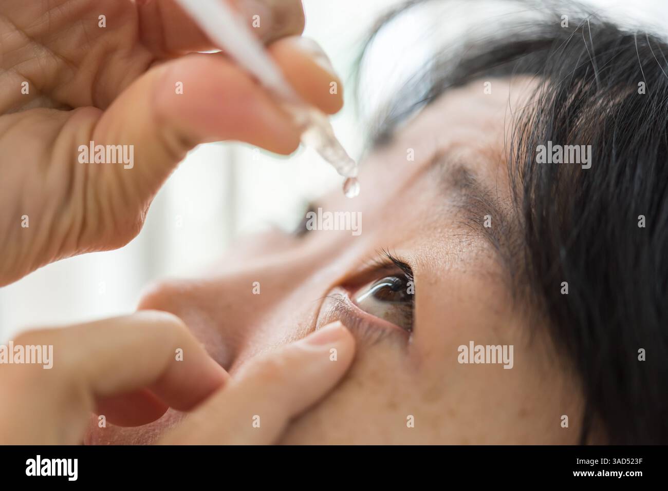 Asian woman use eye drop or artificial tears by drops in to the eye for ...