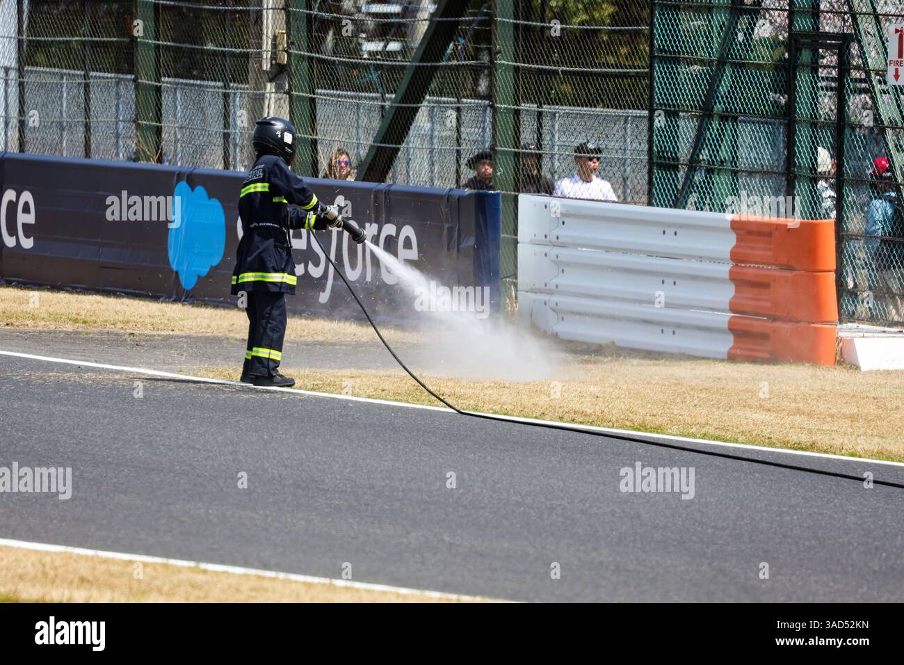 Fire fighter watering the track after the fires caused red flags during ...