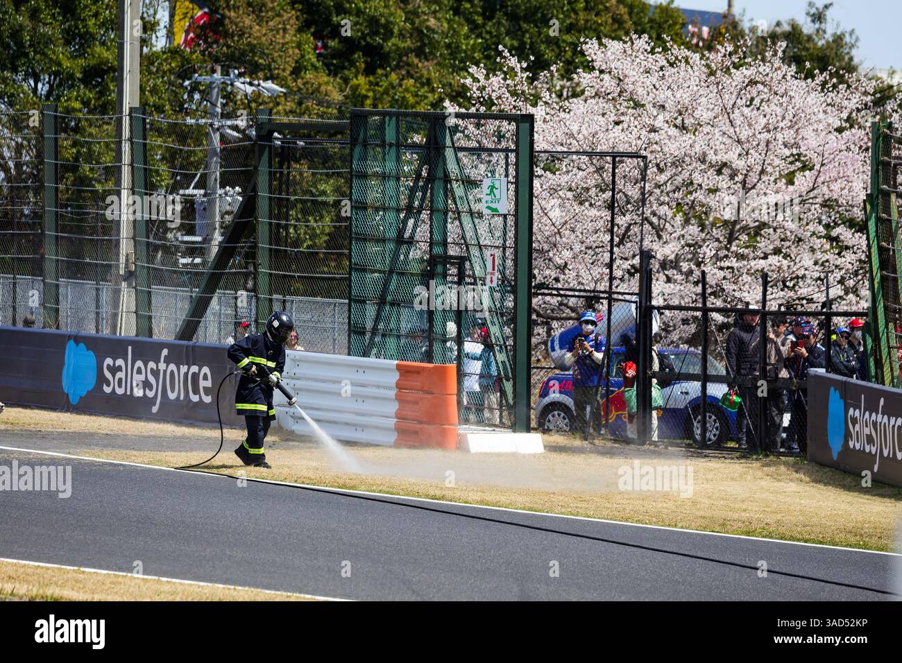 Fire fighter watering the track after the fires caused red flags during ...