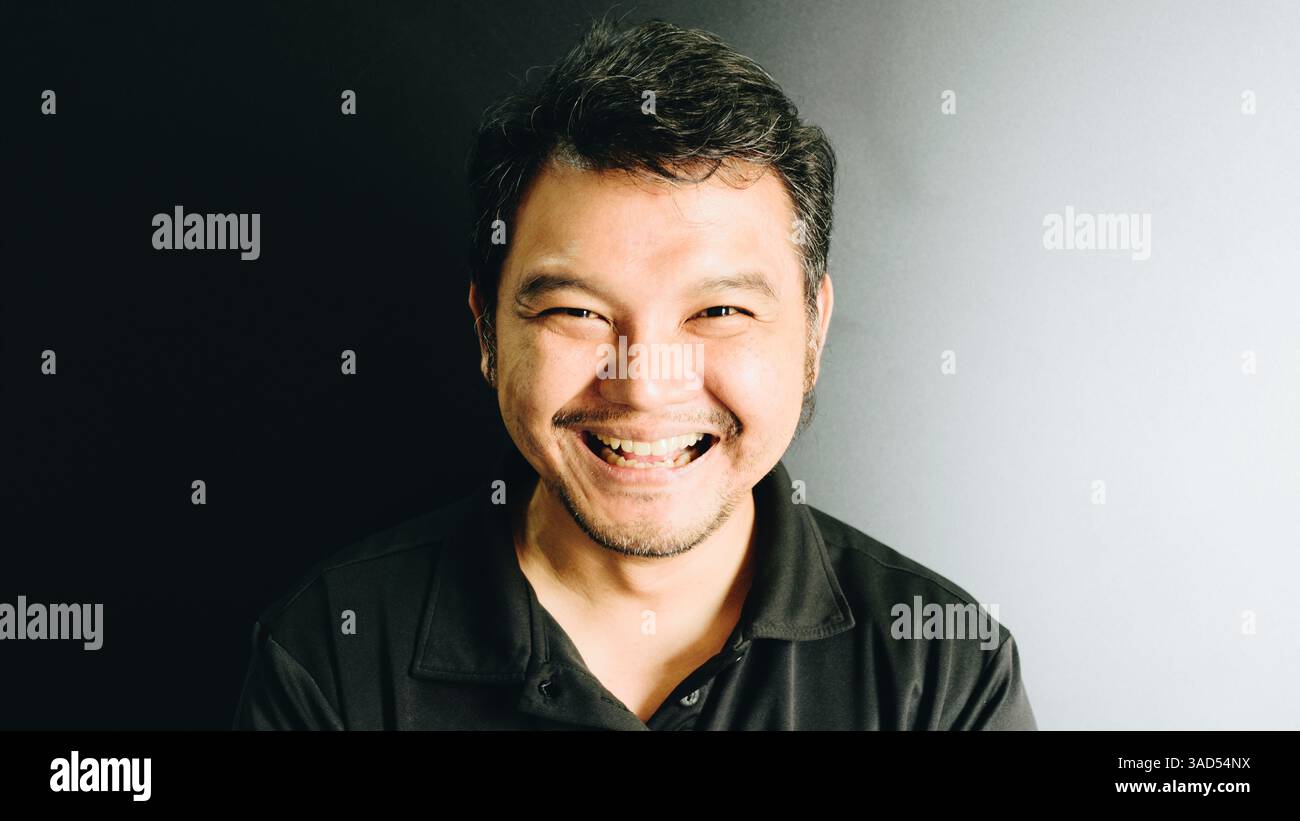 Asia man 40s in black polo shirt have a laughing smile gesture with ...