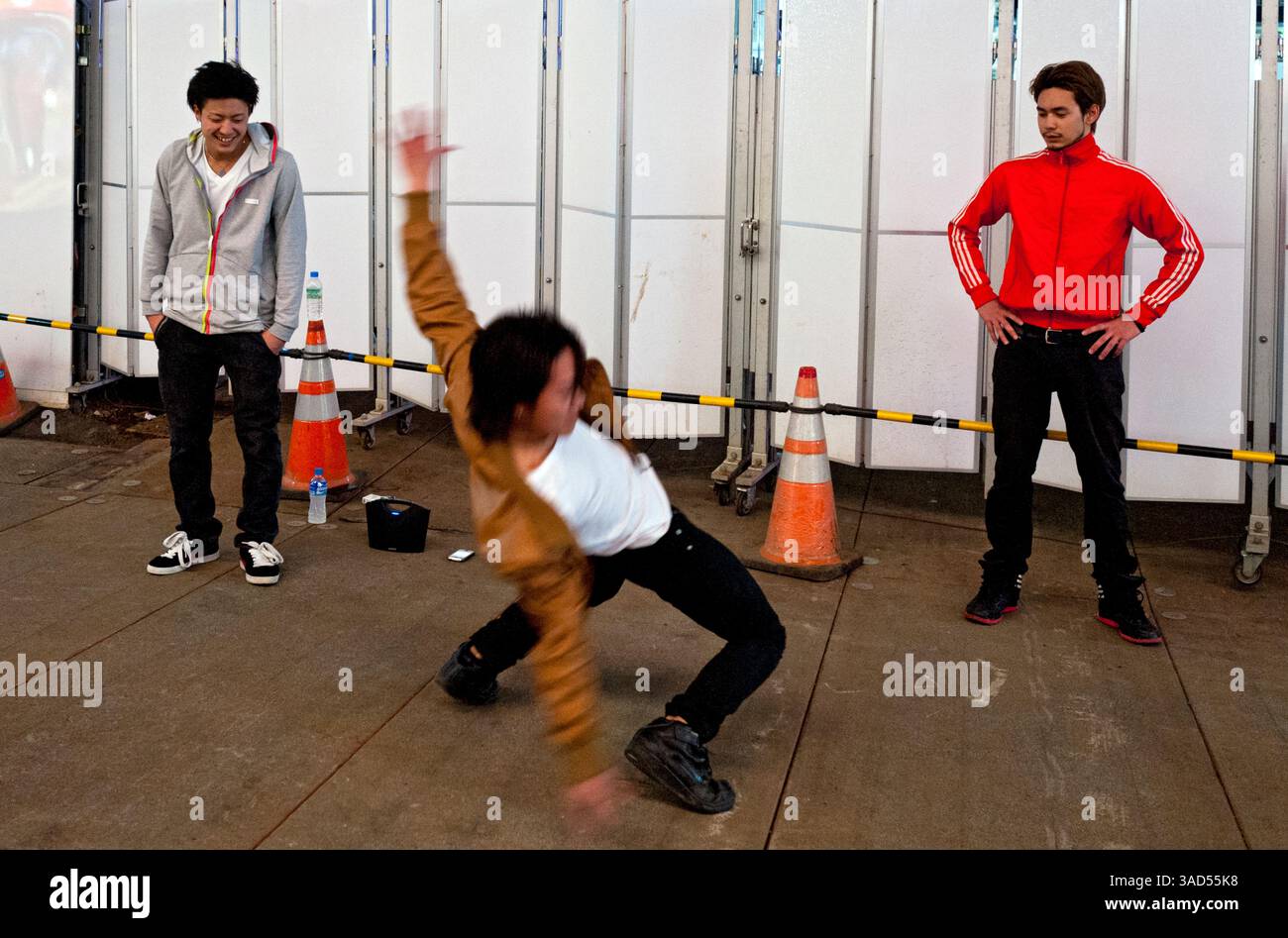 Three boys break dancing to hip-hop music at night in the street in the ...