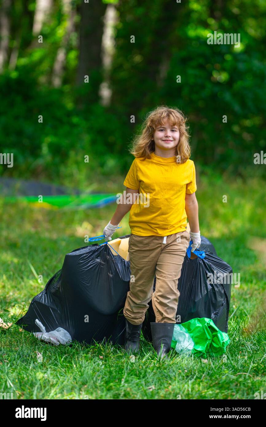 Environment plastic pollution. Volunteer child collecting trash in the forest and holding a ...