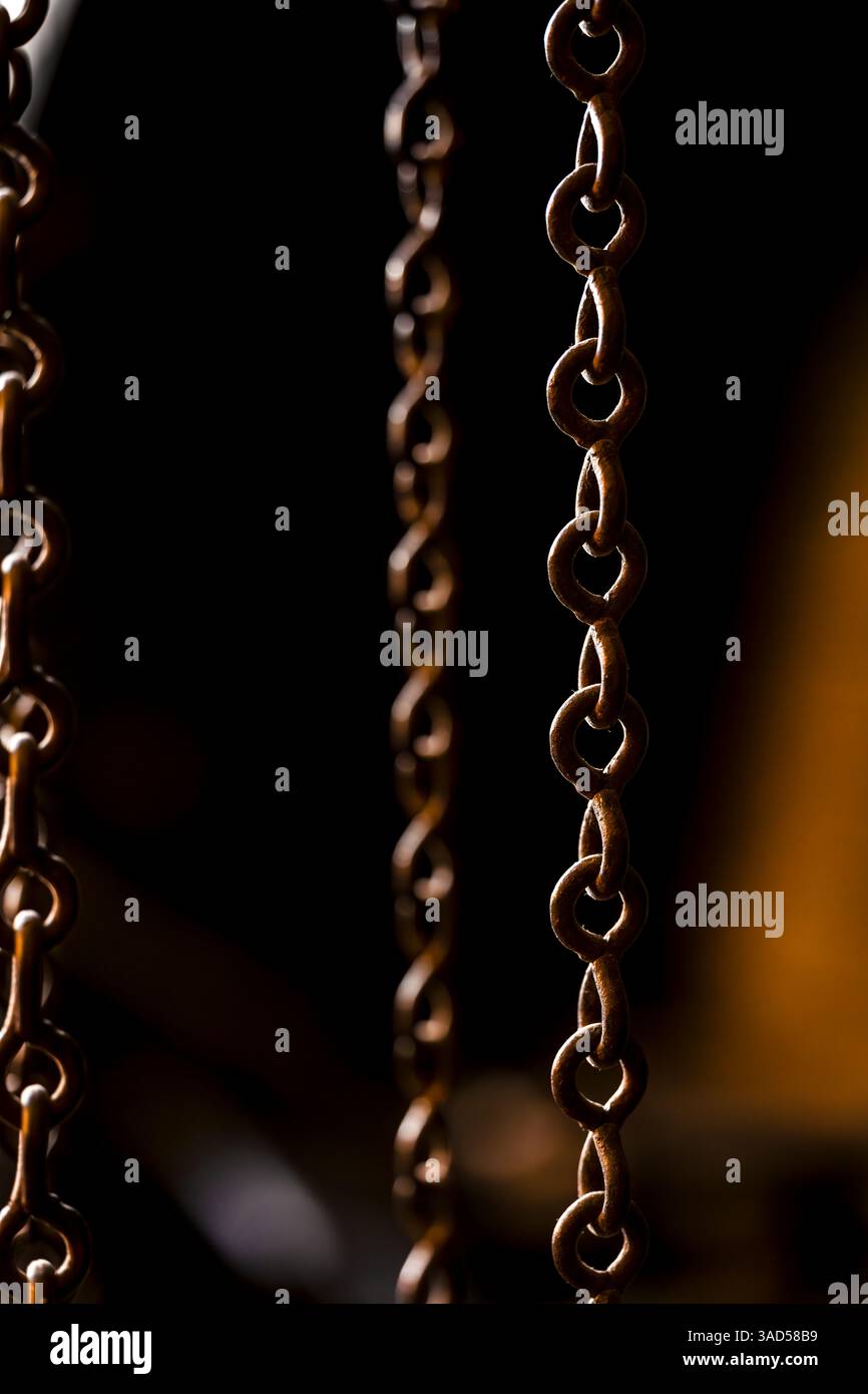 A close-up study of interlinked metal chains suspended in low light ...