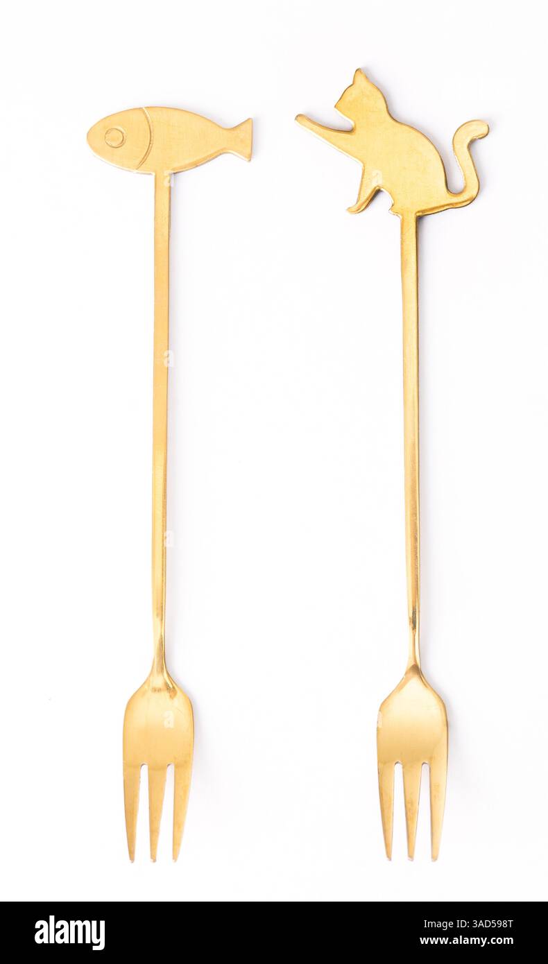 Elegant gold appetizer forks with cat and fish designs on a white ...