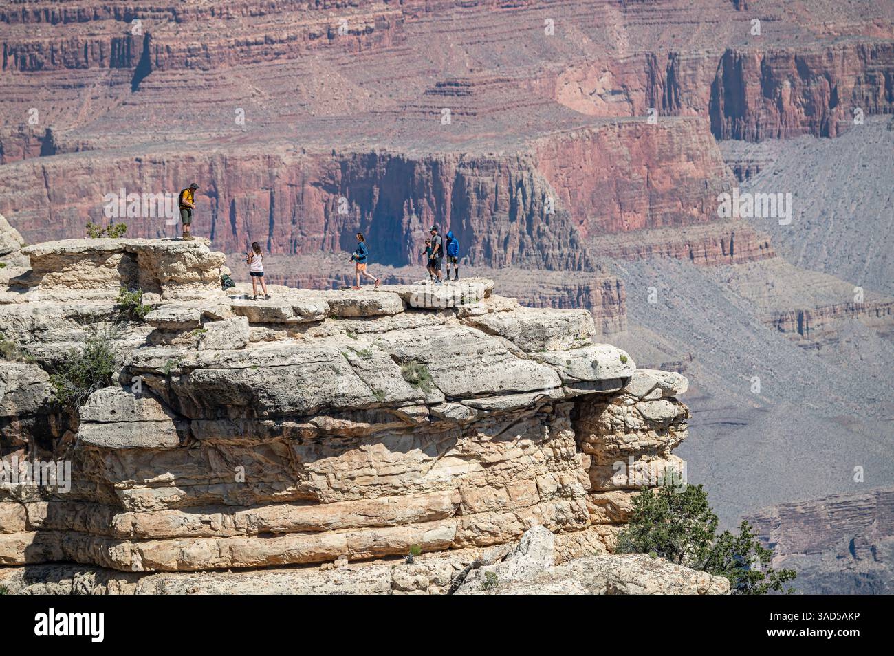 Tourists on the edge of a cliff at the Grand Canyon south rim, Arizona ...