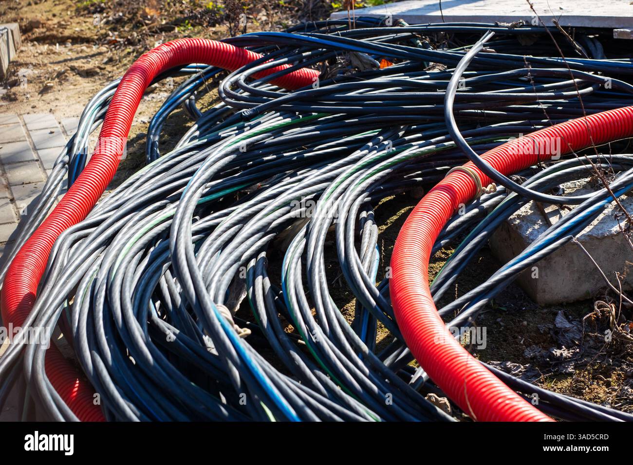A chaotic mix of red and black cables tangled on the ground, showcasing ...