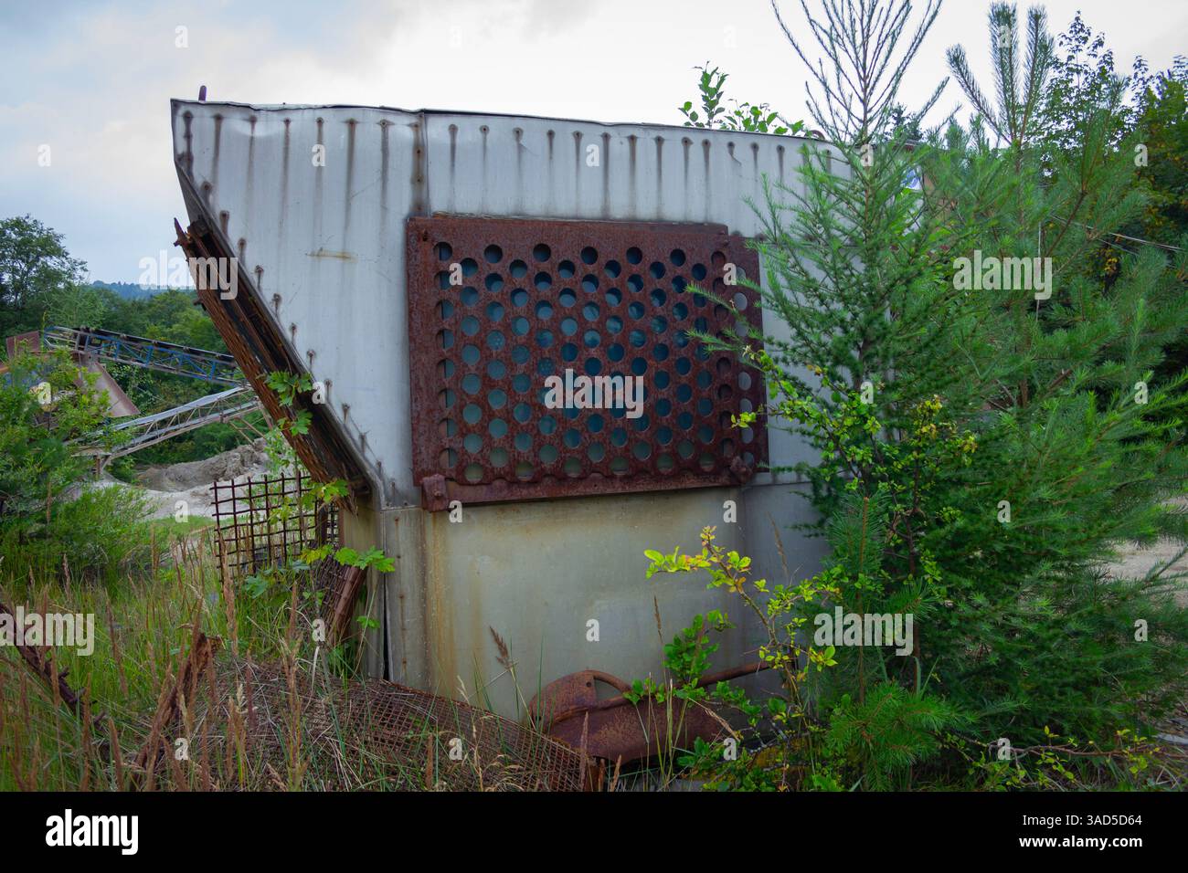 A rusted metal building with a window that is covered in holes. The ...