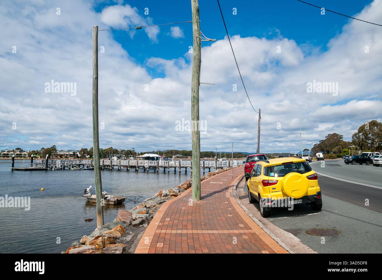 Coastal street with parked cars, marina pier in background, brick ...