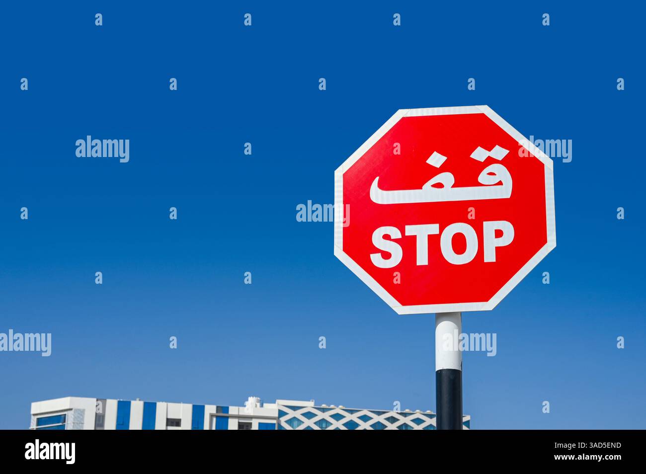 Stop sign with Arabic and English text against blue sky in Oman Stock ...
