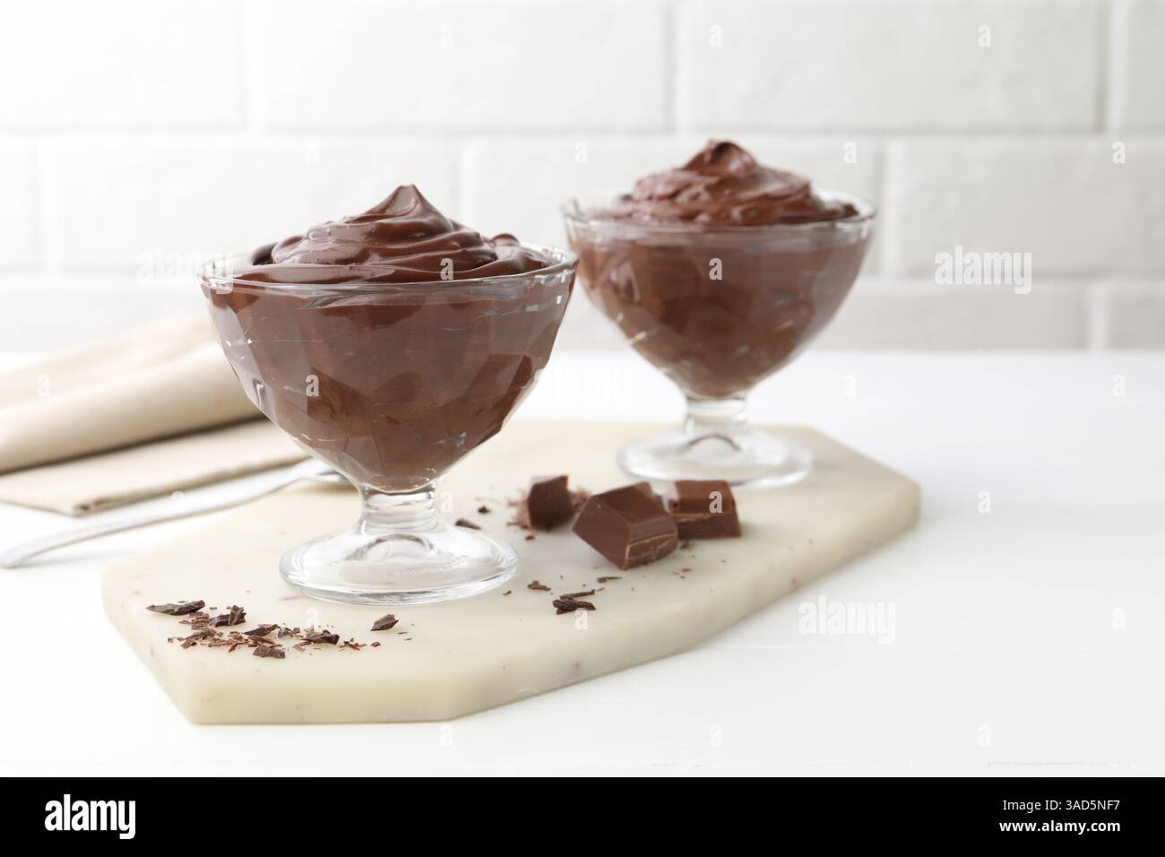 Delicious chocolate pudding in dessert bowls on white table against ...