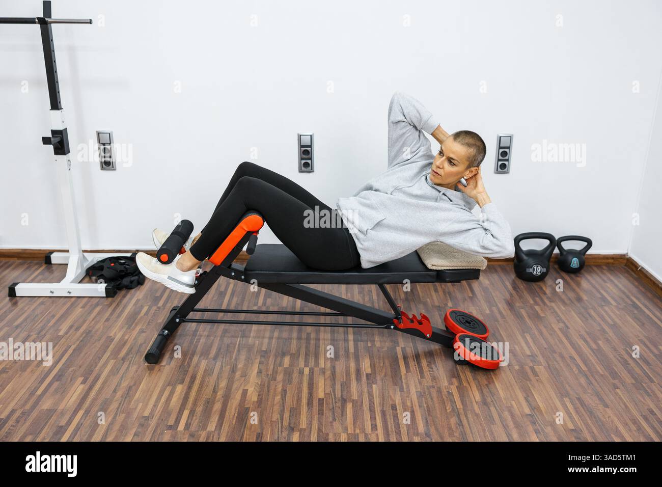 Determined woman performing abdominal crunches on a bench at home gym ...