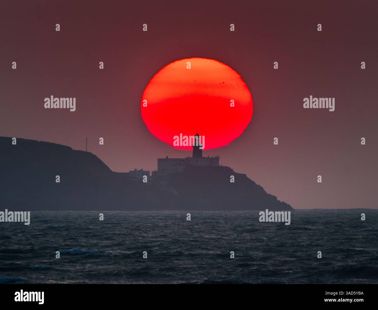Red sunrise over Baily Lighthouse aligned from the Bull Wall. The red ...
